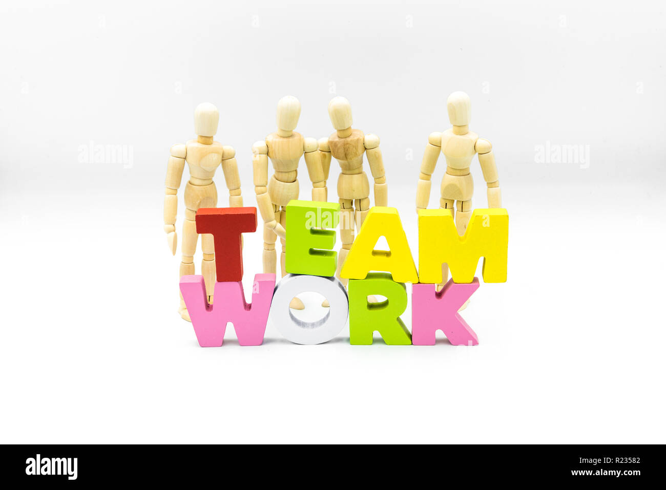 Wooden figures posing as business men behind the word TEAMWORK ...