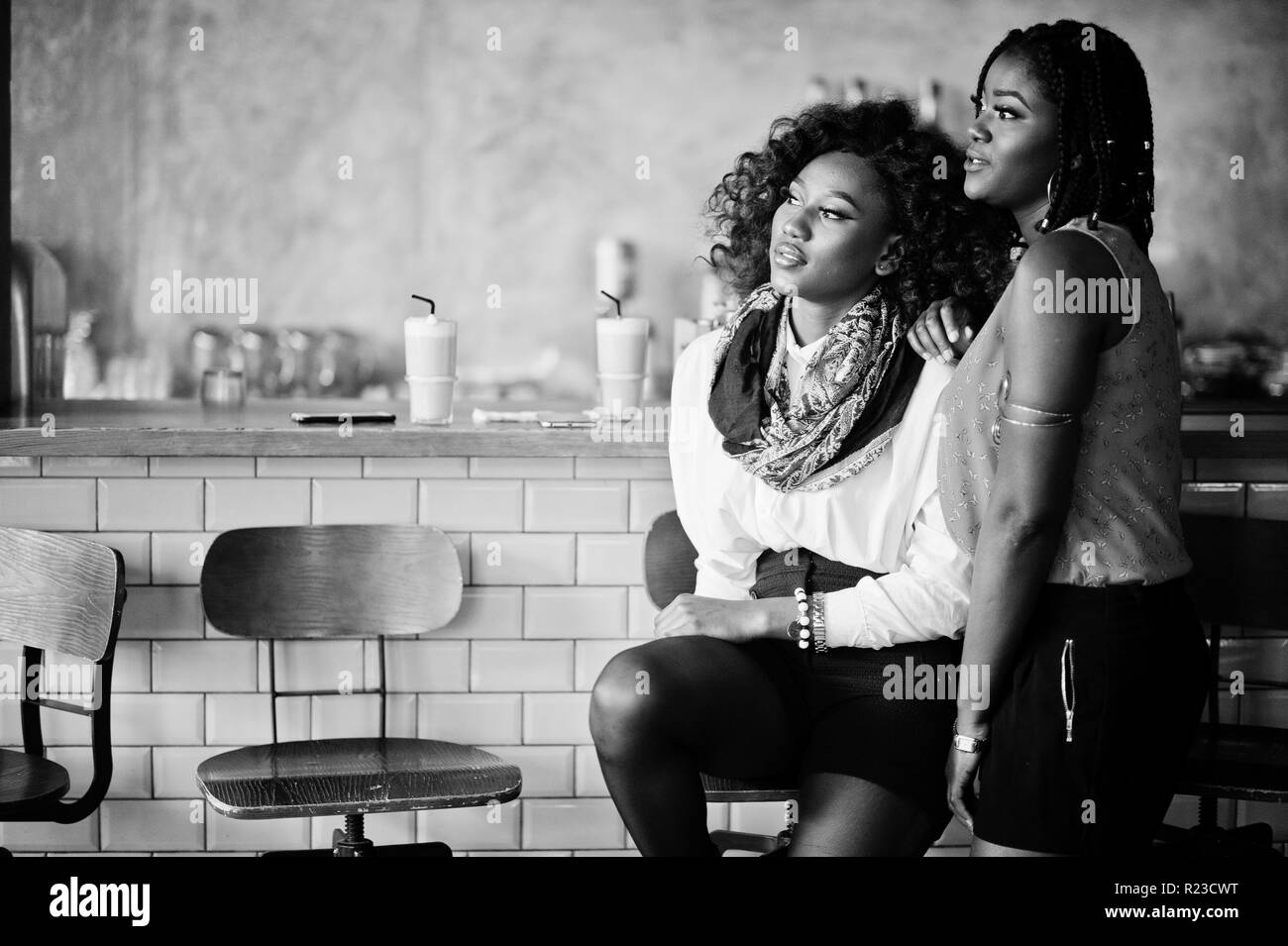 Two girls sitting on chairs Black and White Stock Photos & Images - Alamy