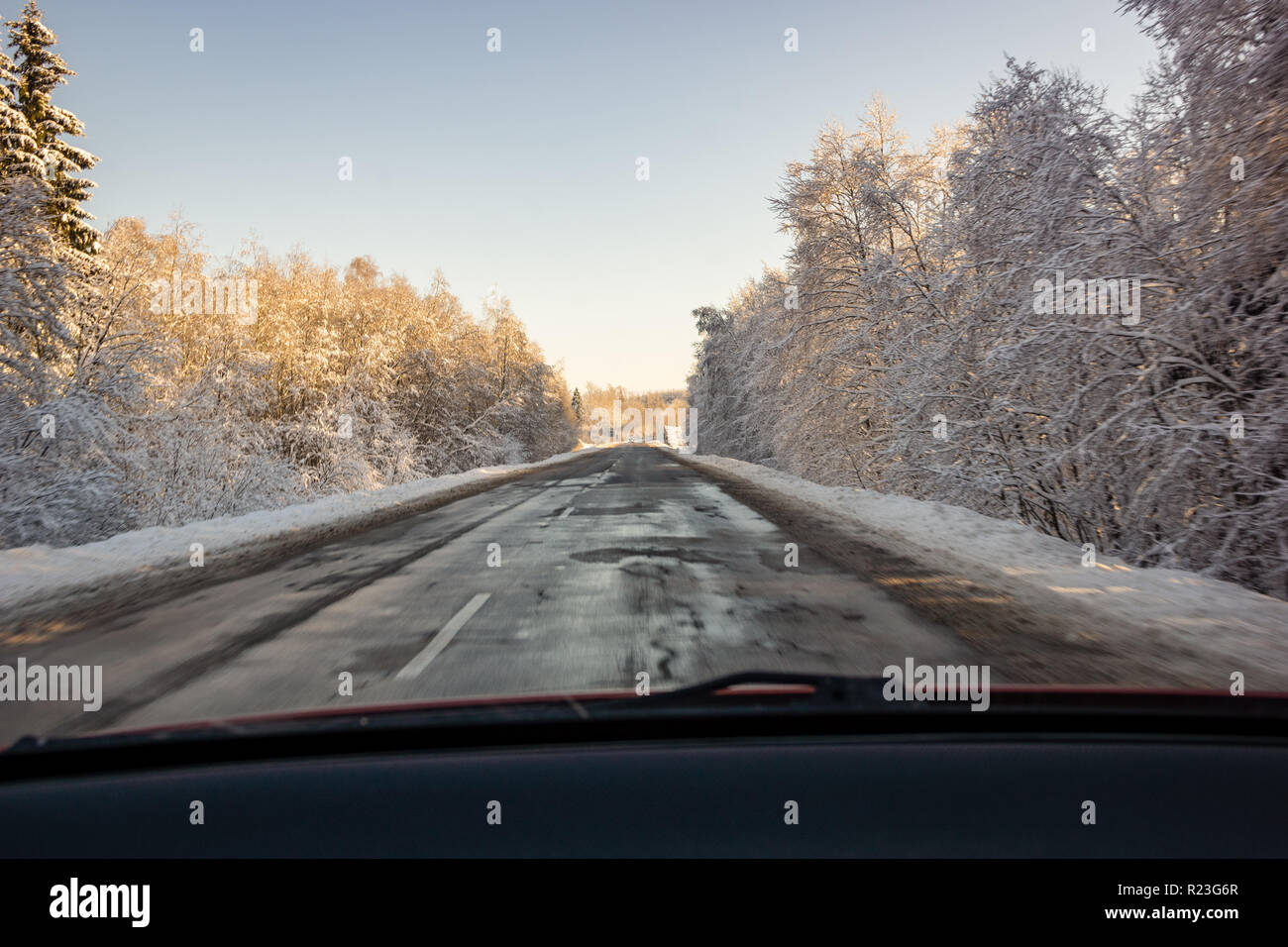 snow and ice covered road in countryside in winter with tire tracks ...