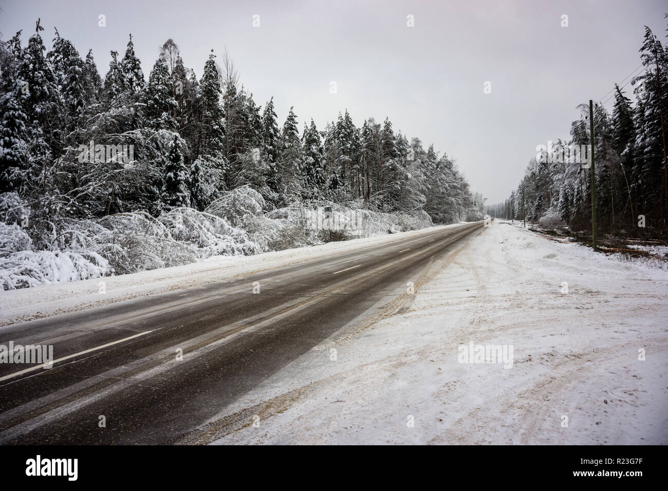 snow and ice covered road in countryside in winter with tire tracks ...