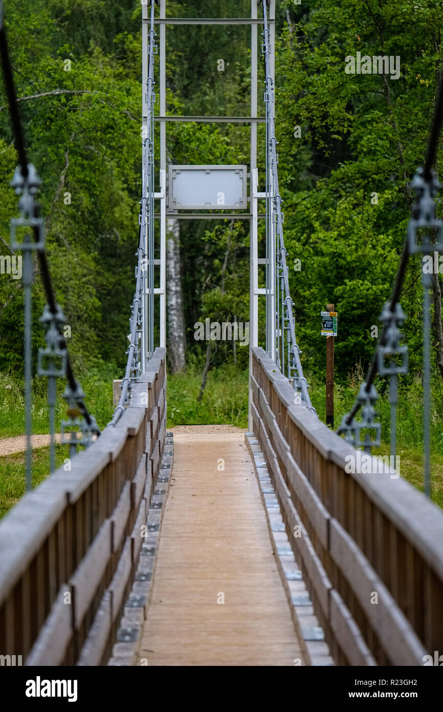 wooden and composite material foot bridge over water in green summer ...