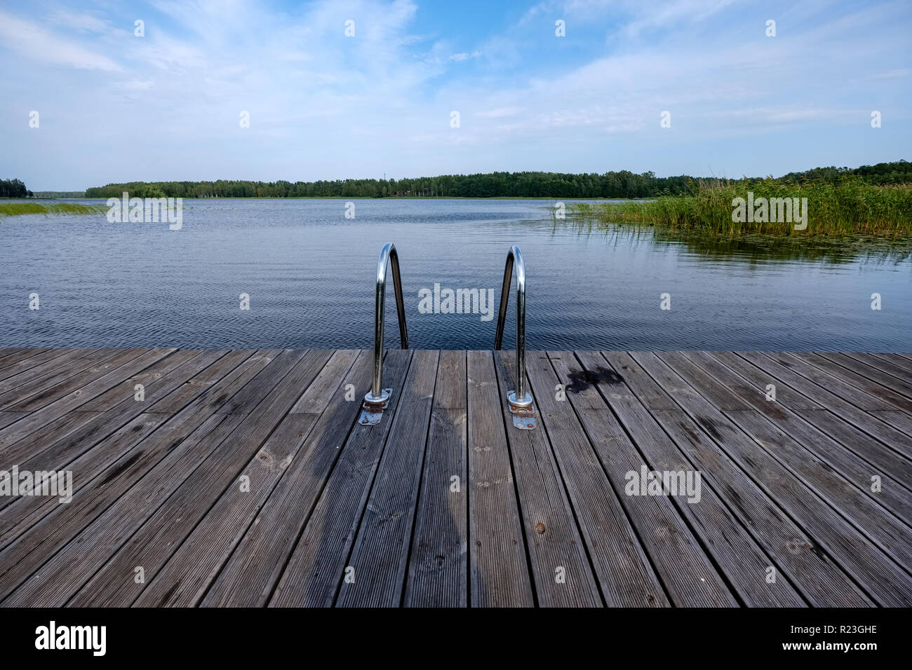 wooden and composite material foot bridge over water in green summer ...