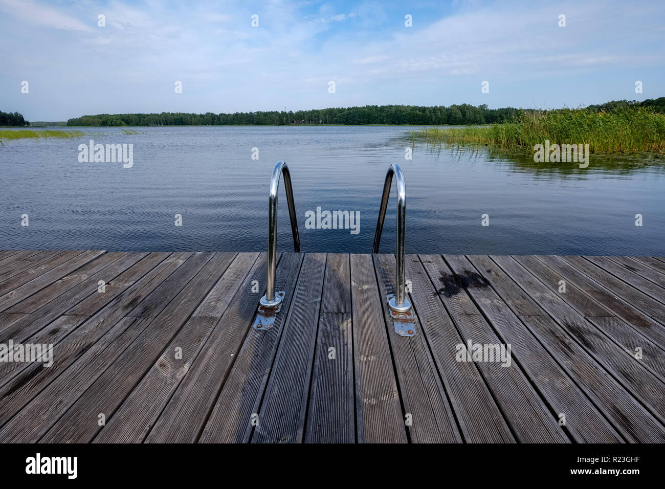wooden and composite material foot bridge over water in green summer ...