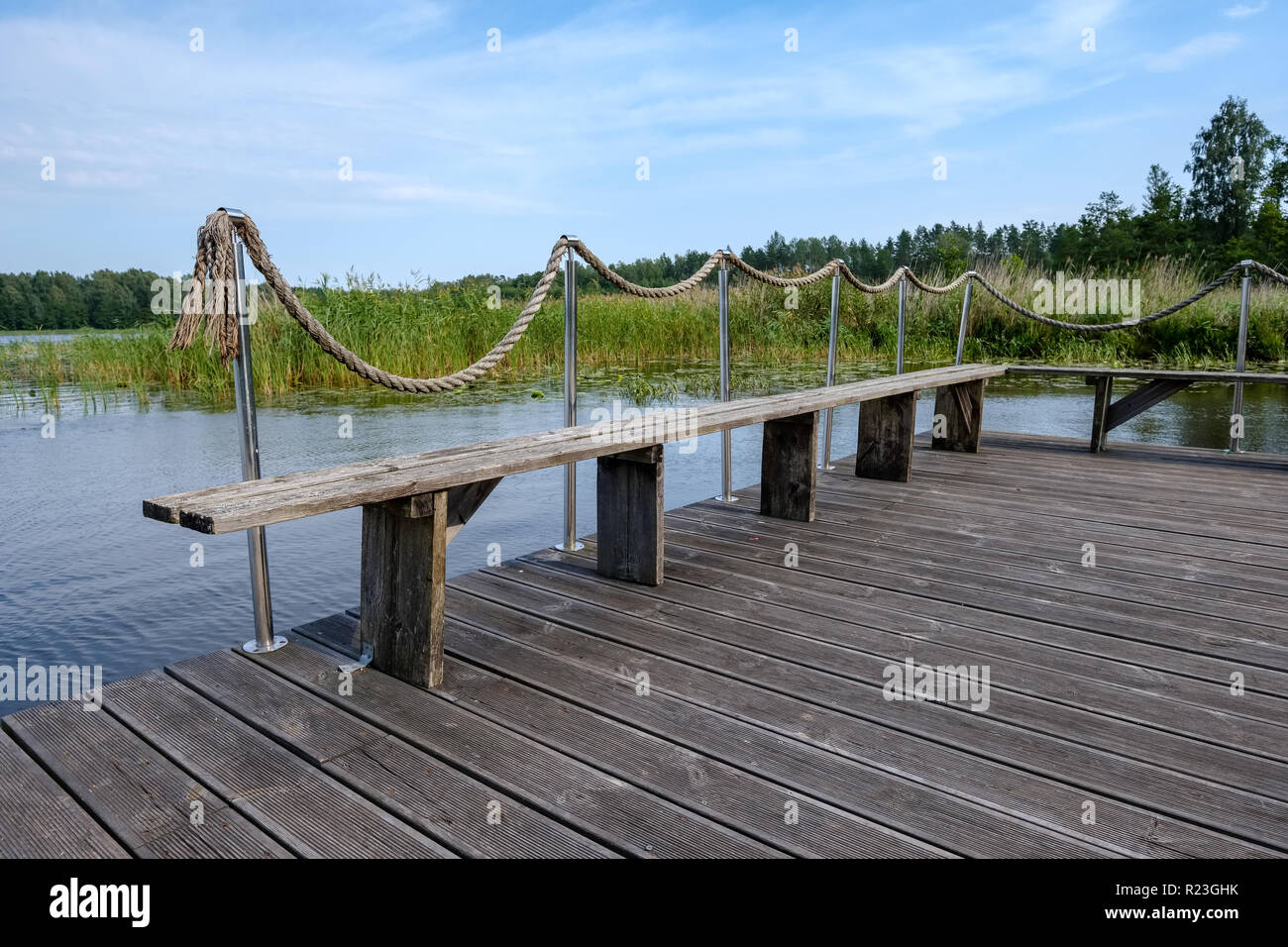 wooden and composite material foot bridge over water in green summer ...
