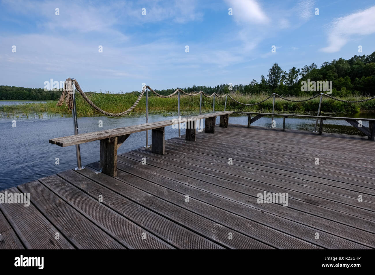 wooden and composite material foot bridge over water in green summer ...