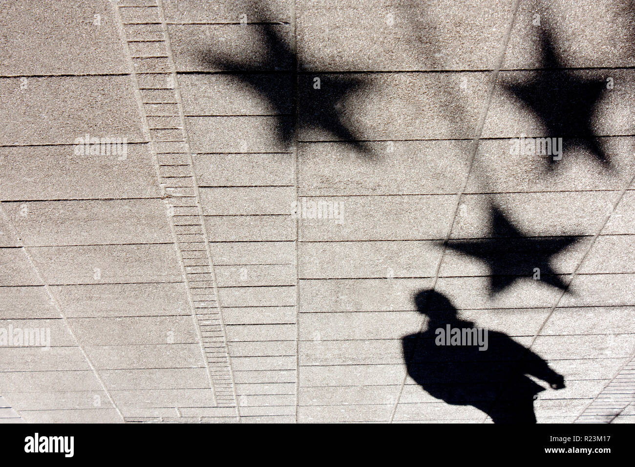 Shadow silhouette of a man under star shaped ornaments on city street ...