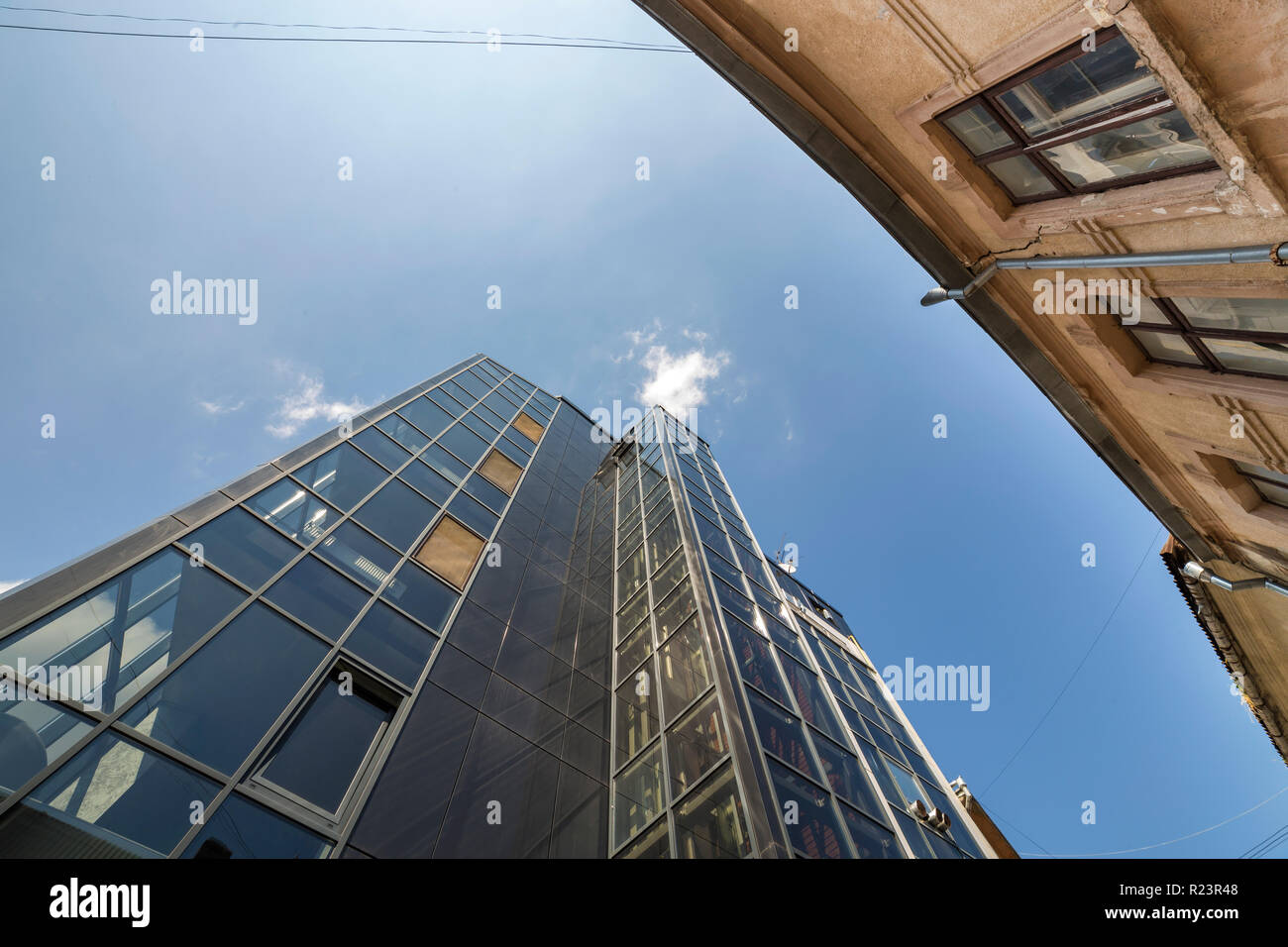 Bottom view of tall building with glass wall opposite neglected ...
