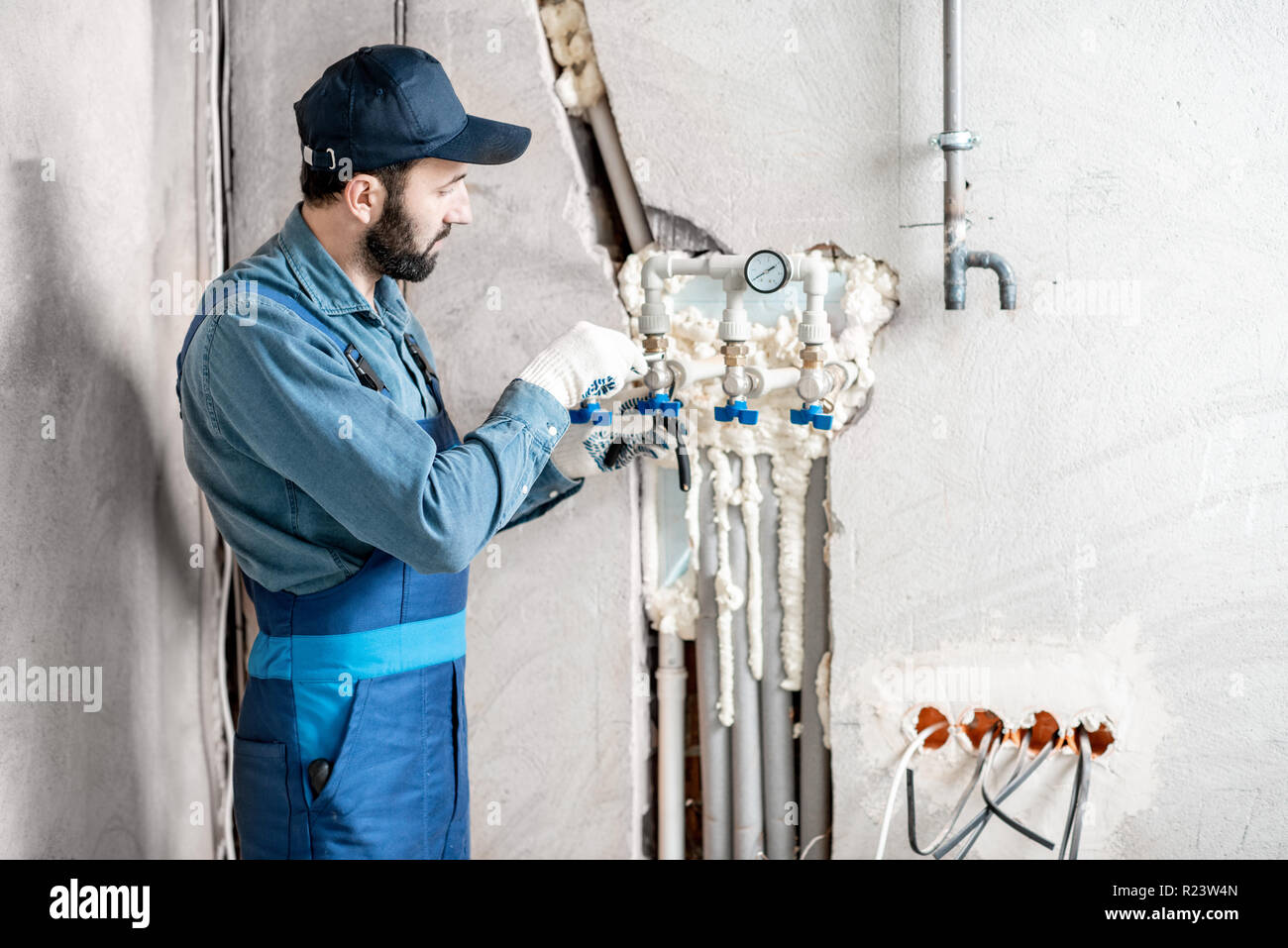 Workman in blue uniform installing water heating system on the ...