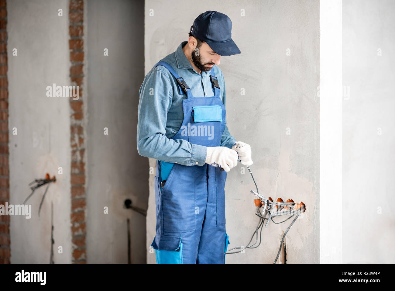 Electrician mounting wiring for electric sockets on the construction ...
