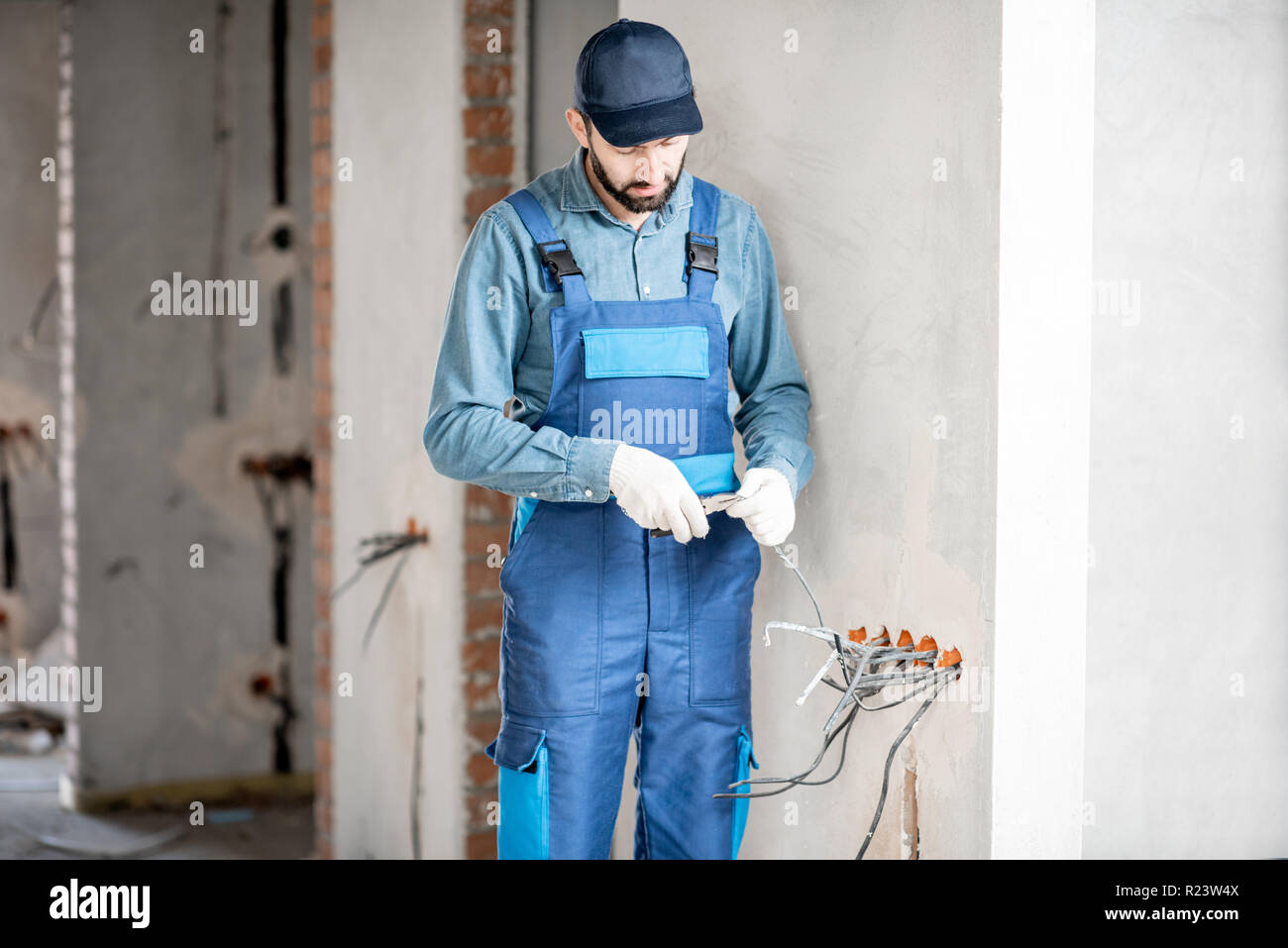 Electrician mounting wiring for electric sockets on the construction ...