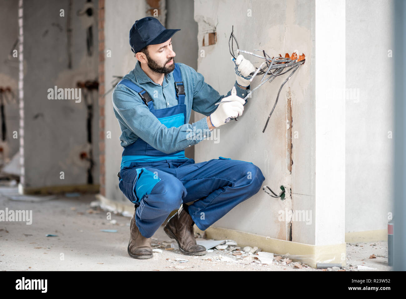 Electrician mounting wiring for electric sockets on the construction ...