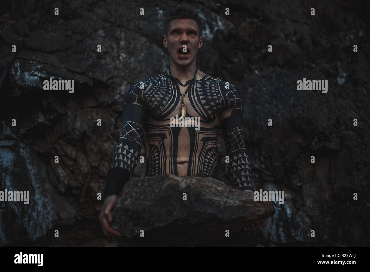 A fury man in armor with a trident and a big stone in his hands against ...