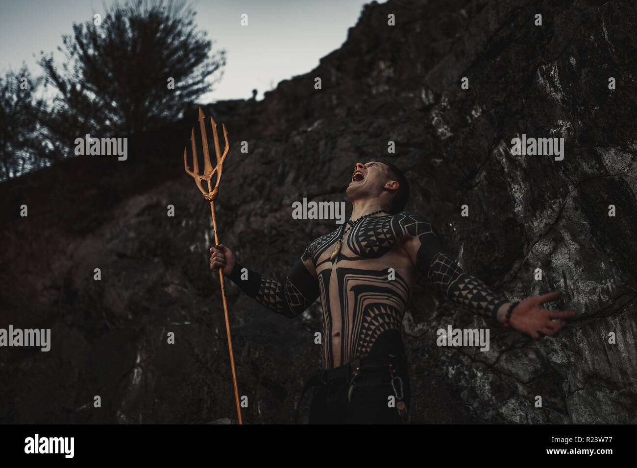 A fury man in armor and with a trident in his hands against the ...