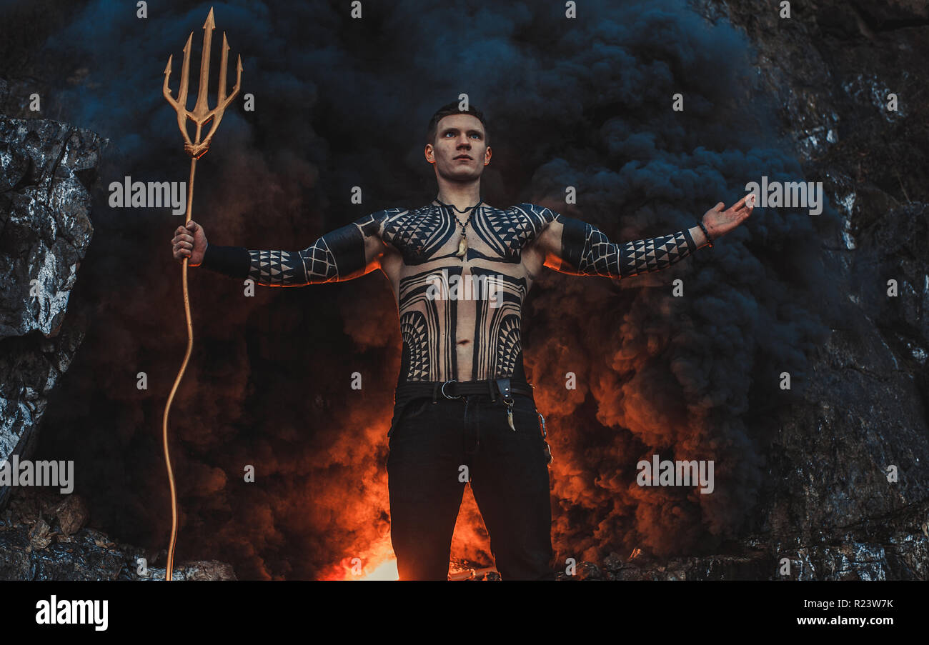 A young man in armor and with a trident in his hands against the ...