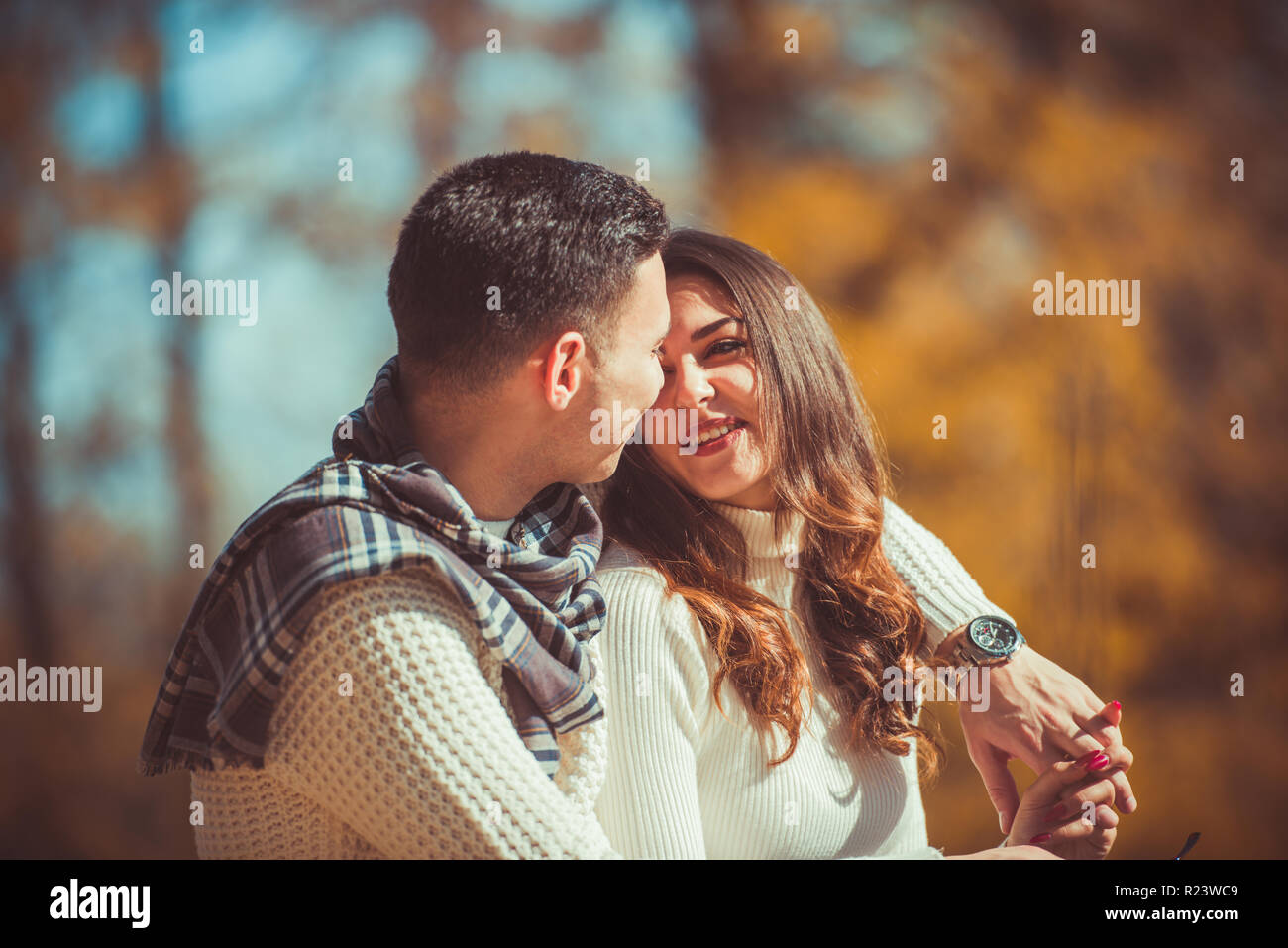 Good looking couple is sitting on the gras in the park, they are ...