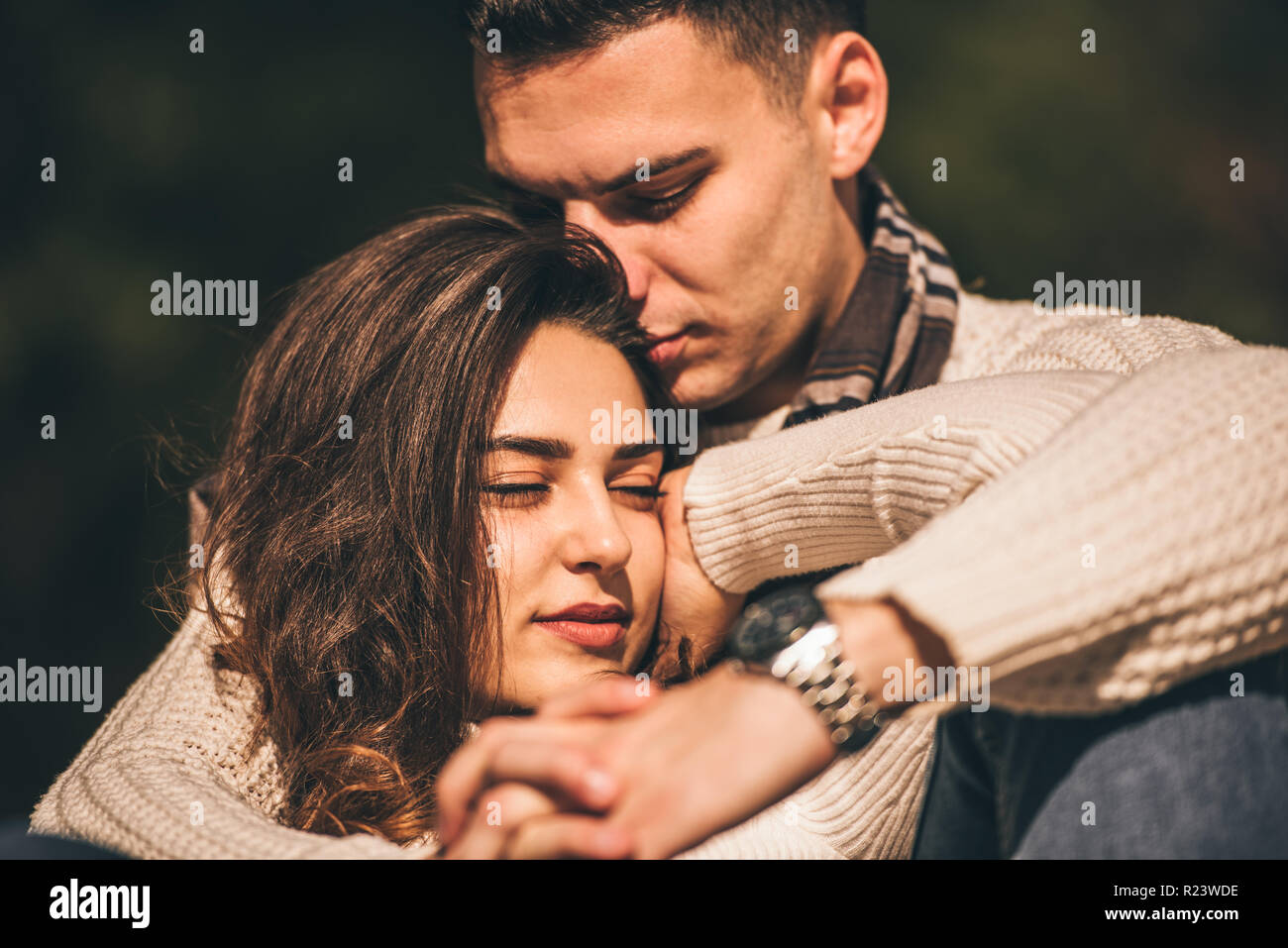 Divine couple is sitting by the river in the park and spending quality ...