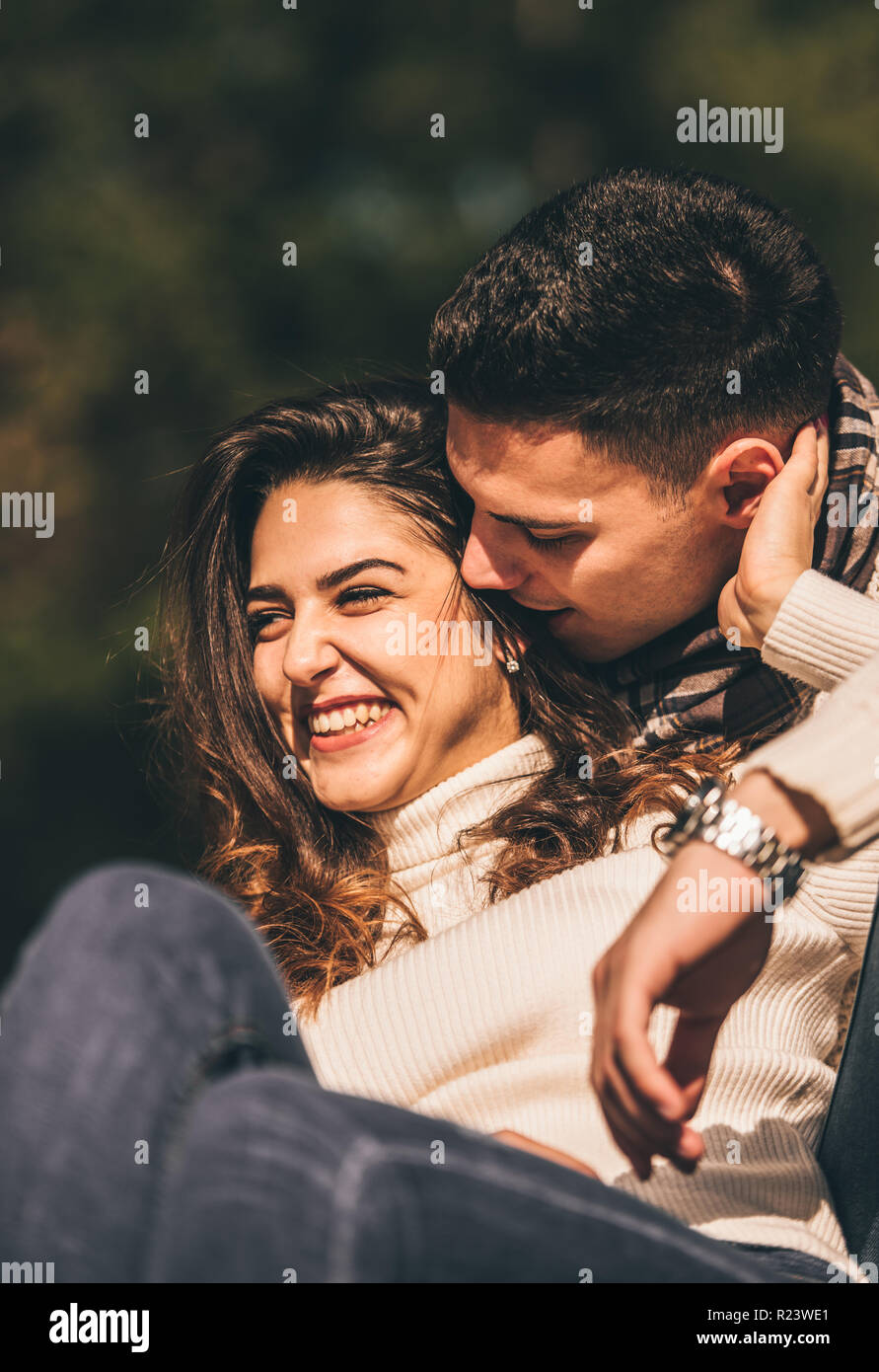 Good looking couple is lying on the gras in the park, they are smiling ...