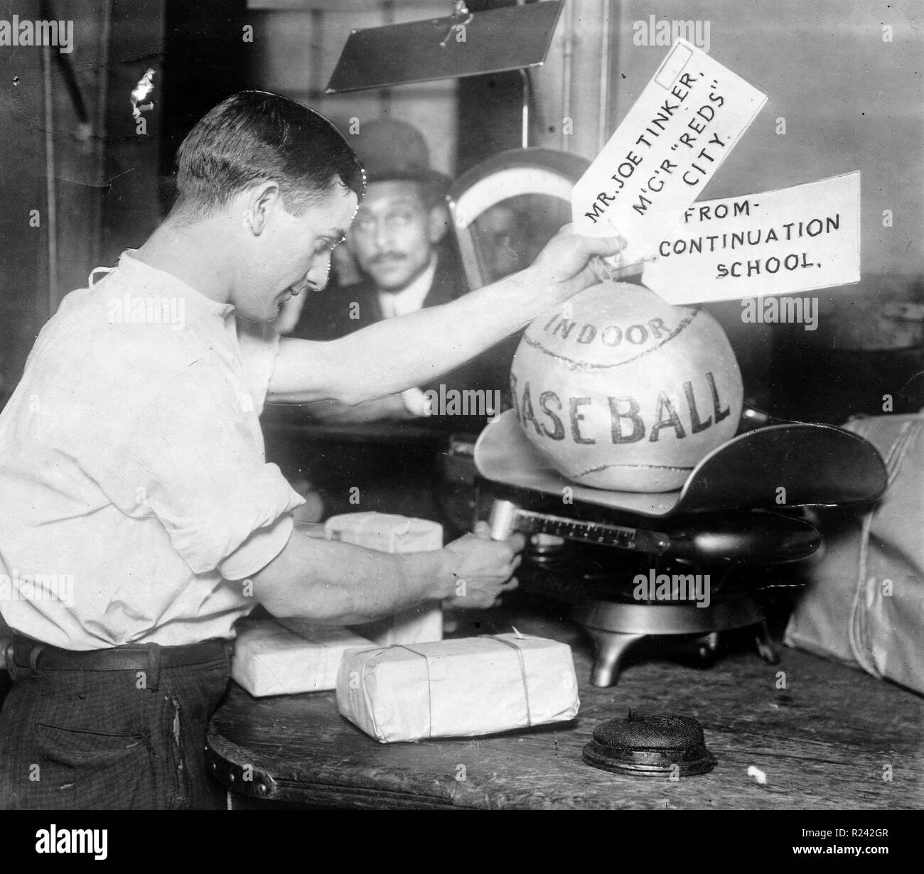 Medicine ball being weighed by American Post Office employee 1910. A ...