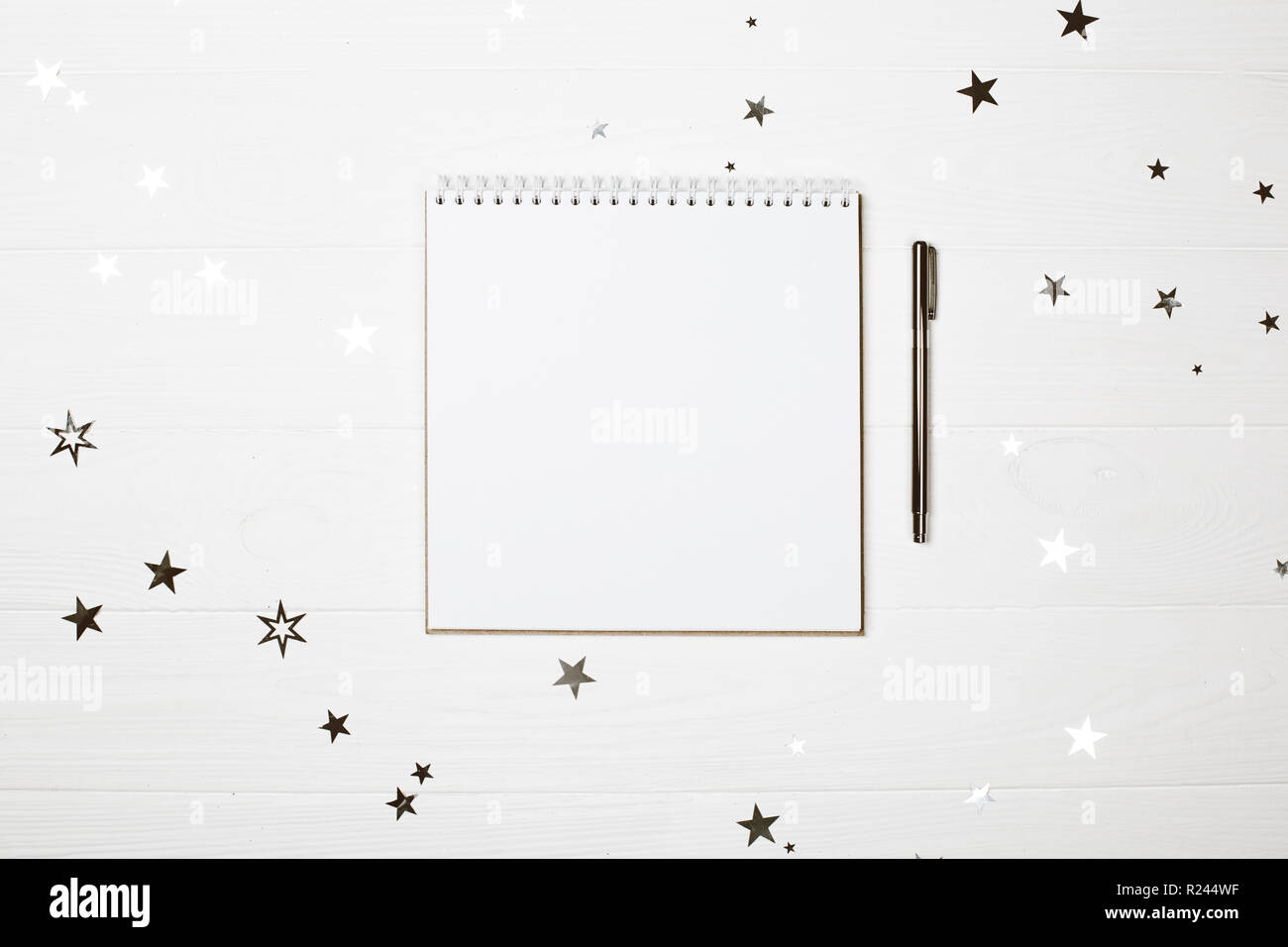 White square shaped notebook with pen on white wooden background ...