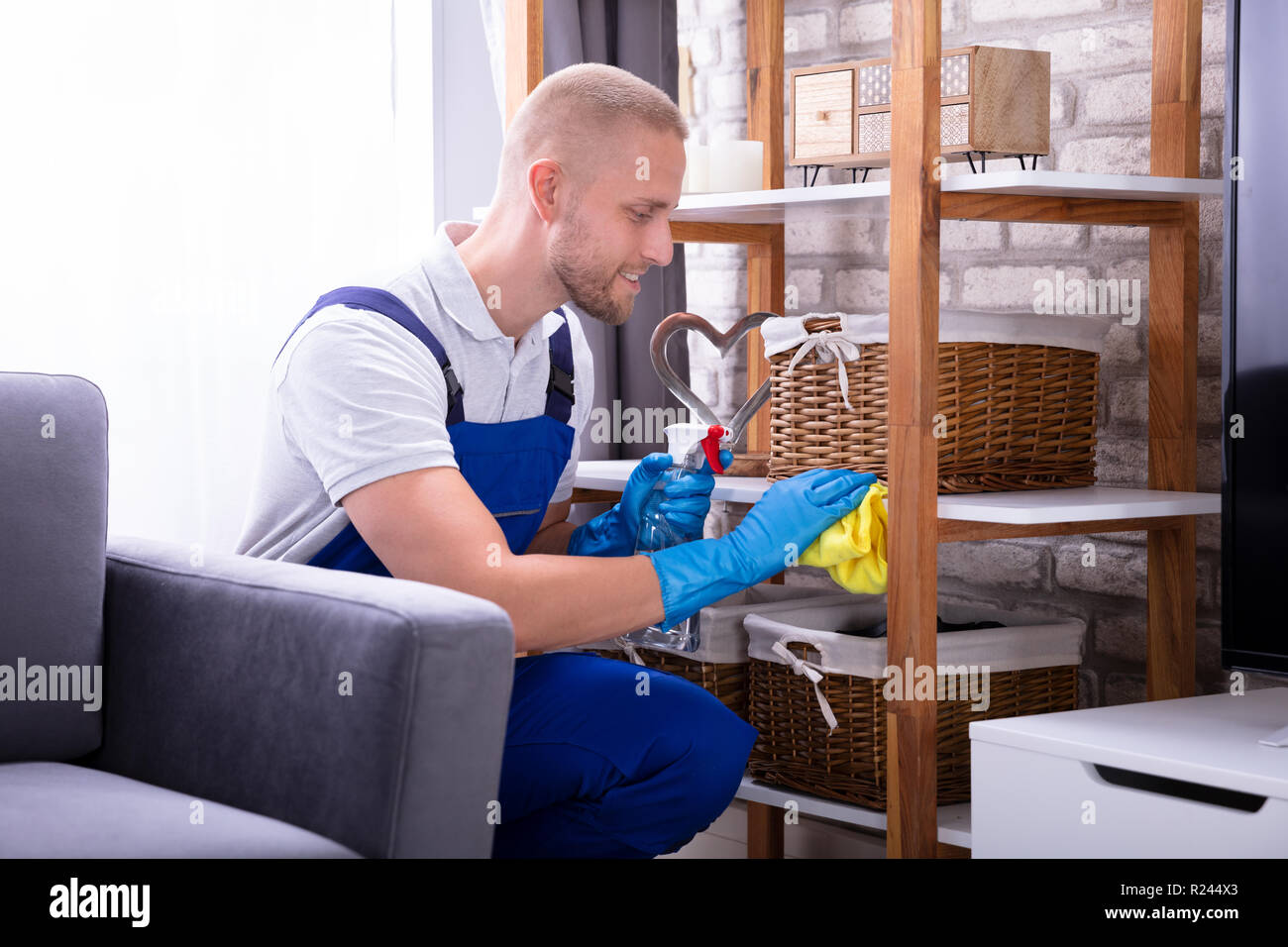 Smiling Male Janitor In Uniform Wiping Wooden Shelf Stock Photo - Alamy