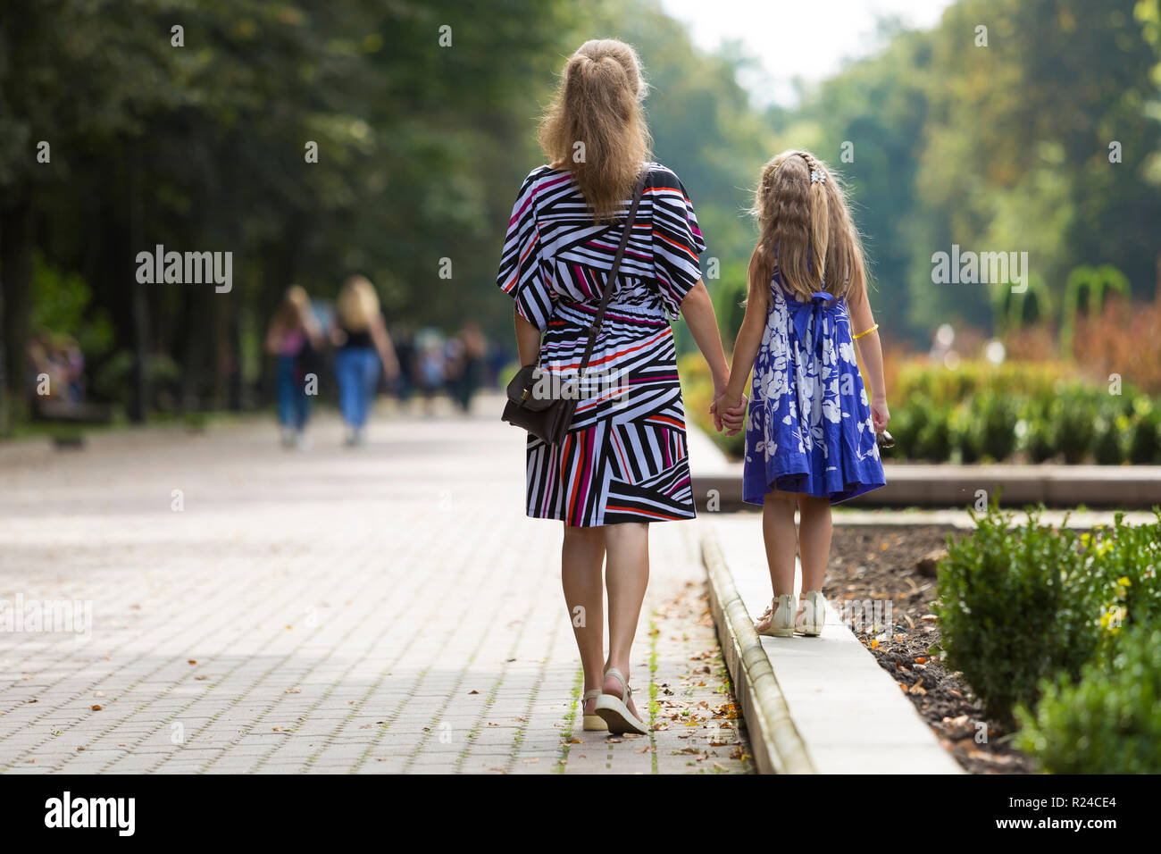 Back view of young blond long-haired slim attractive woman and small ...