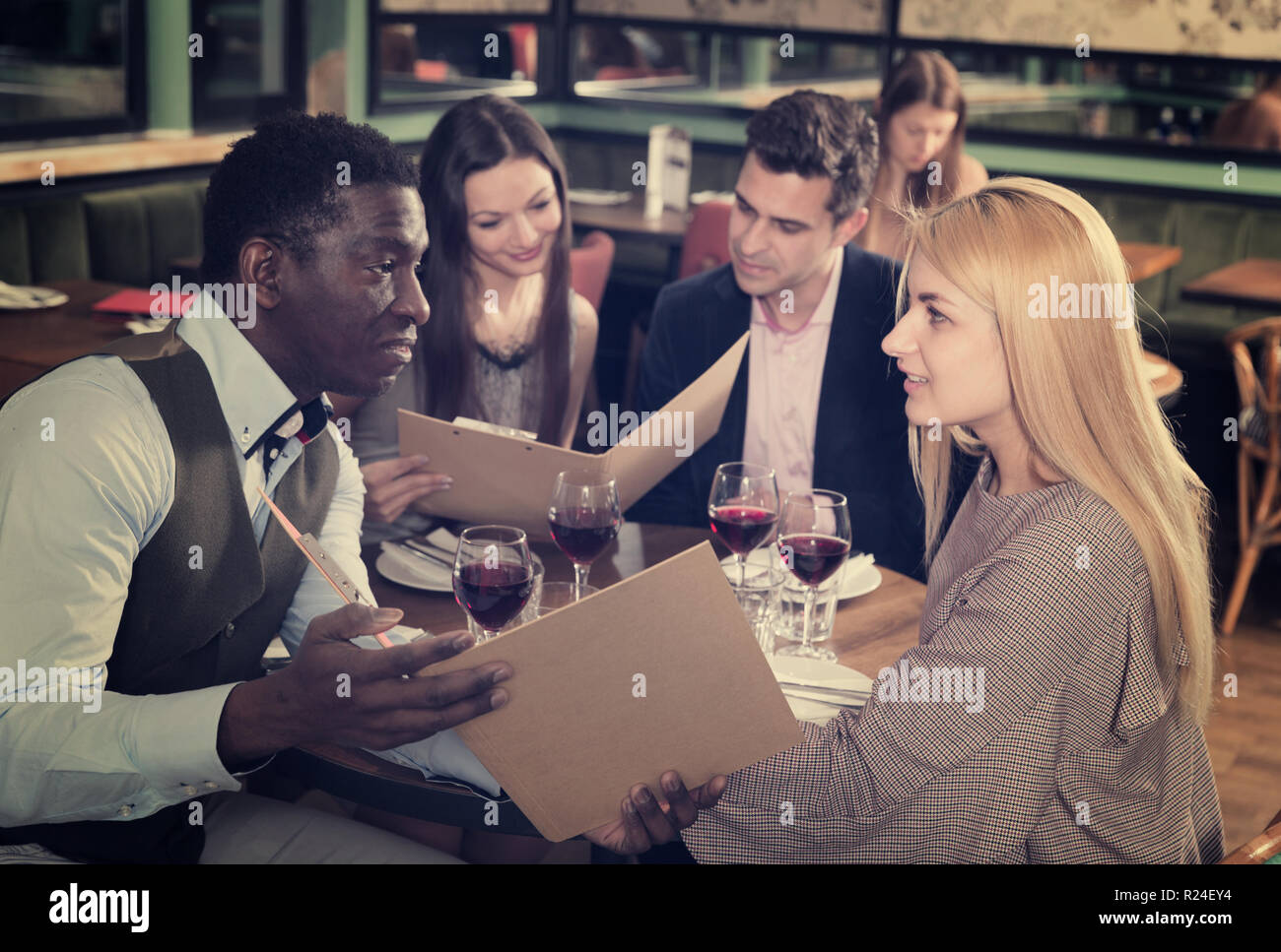 Group of friends enjoying meeting at restaurant, choosing meal from ...