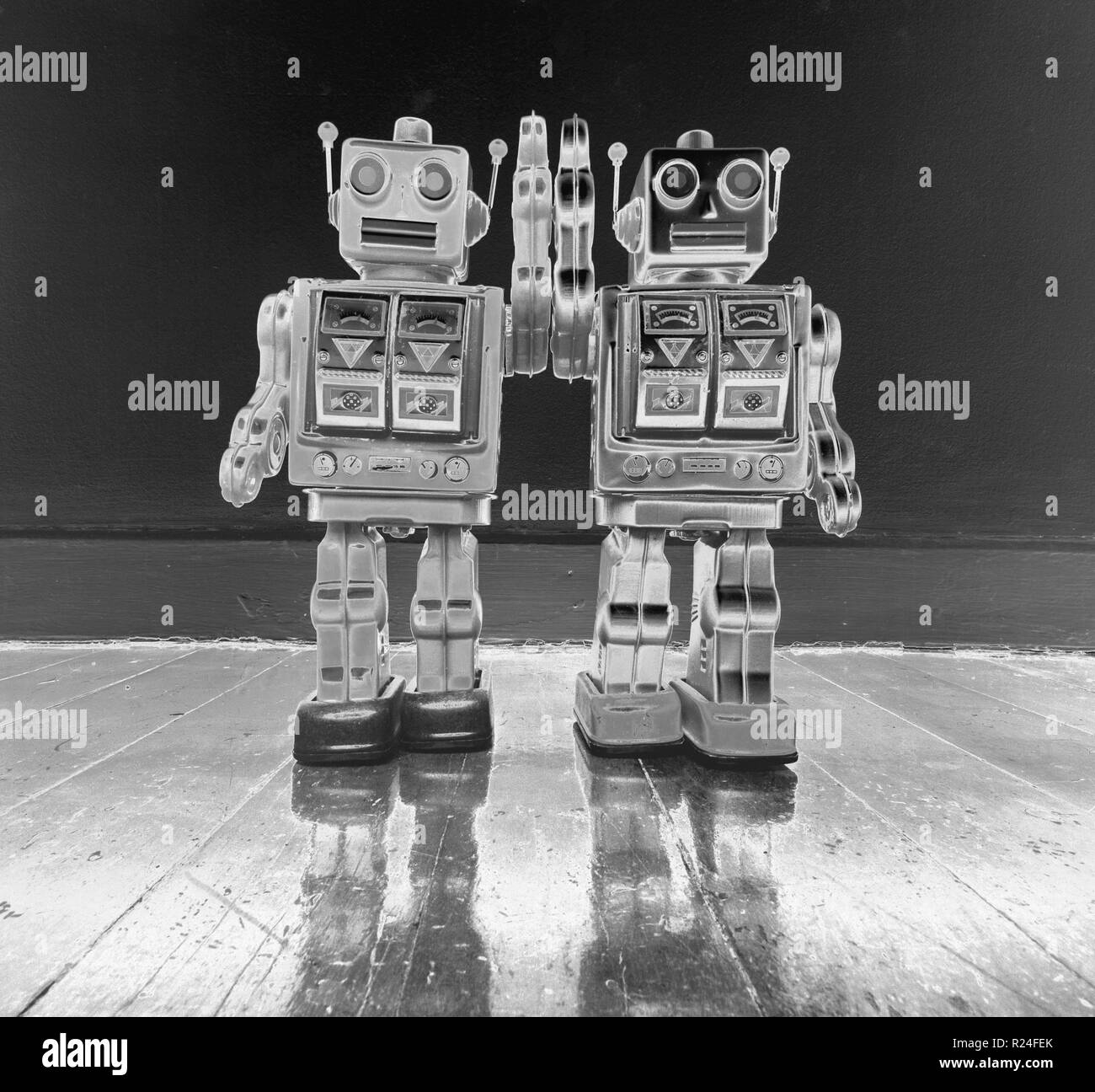 two vintage robot toy happy together on a wooden floor with reflection ...