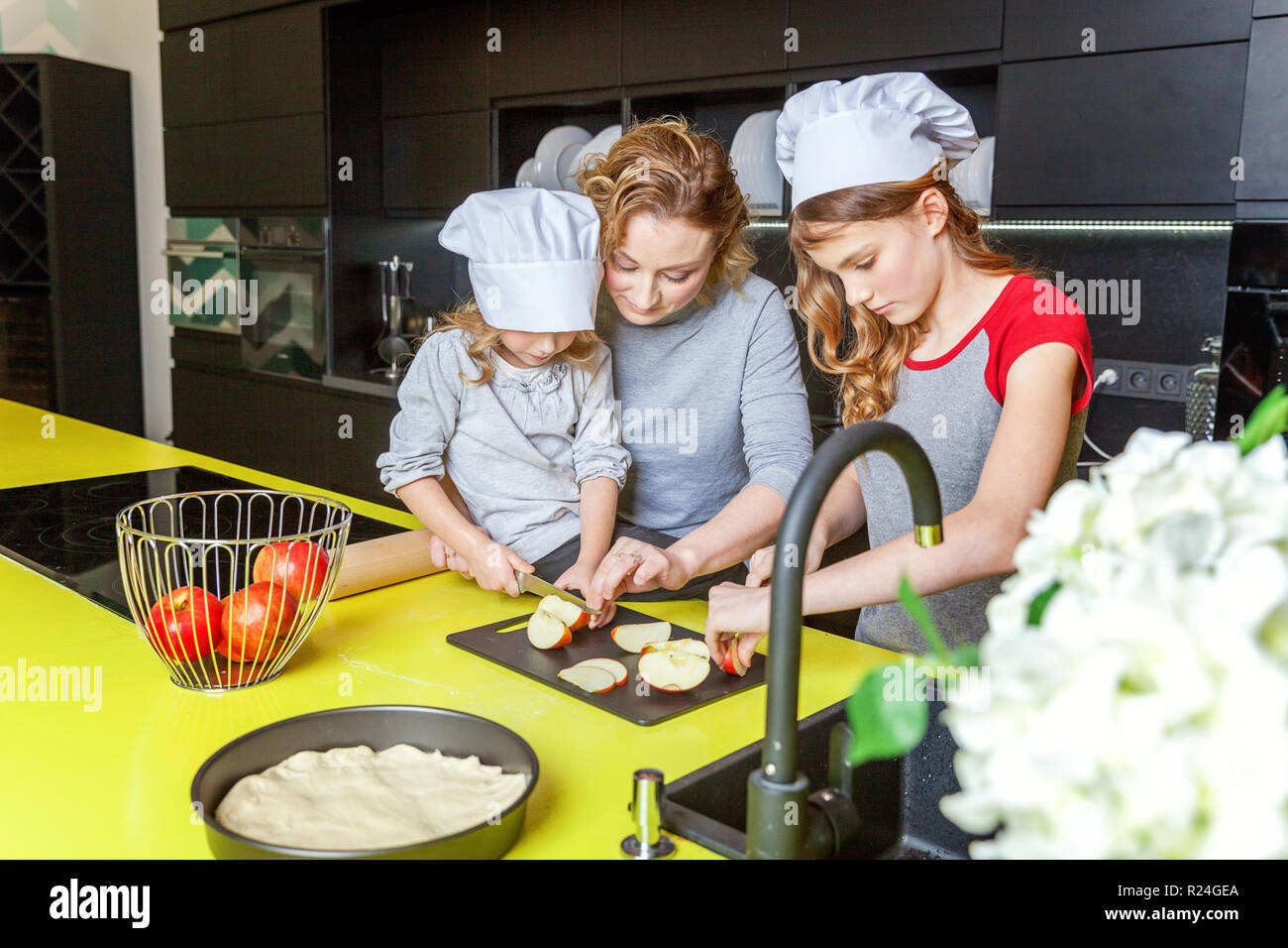 Happy family in kitchen. Mother and two children preparing dough, bake ...