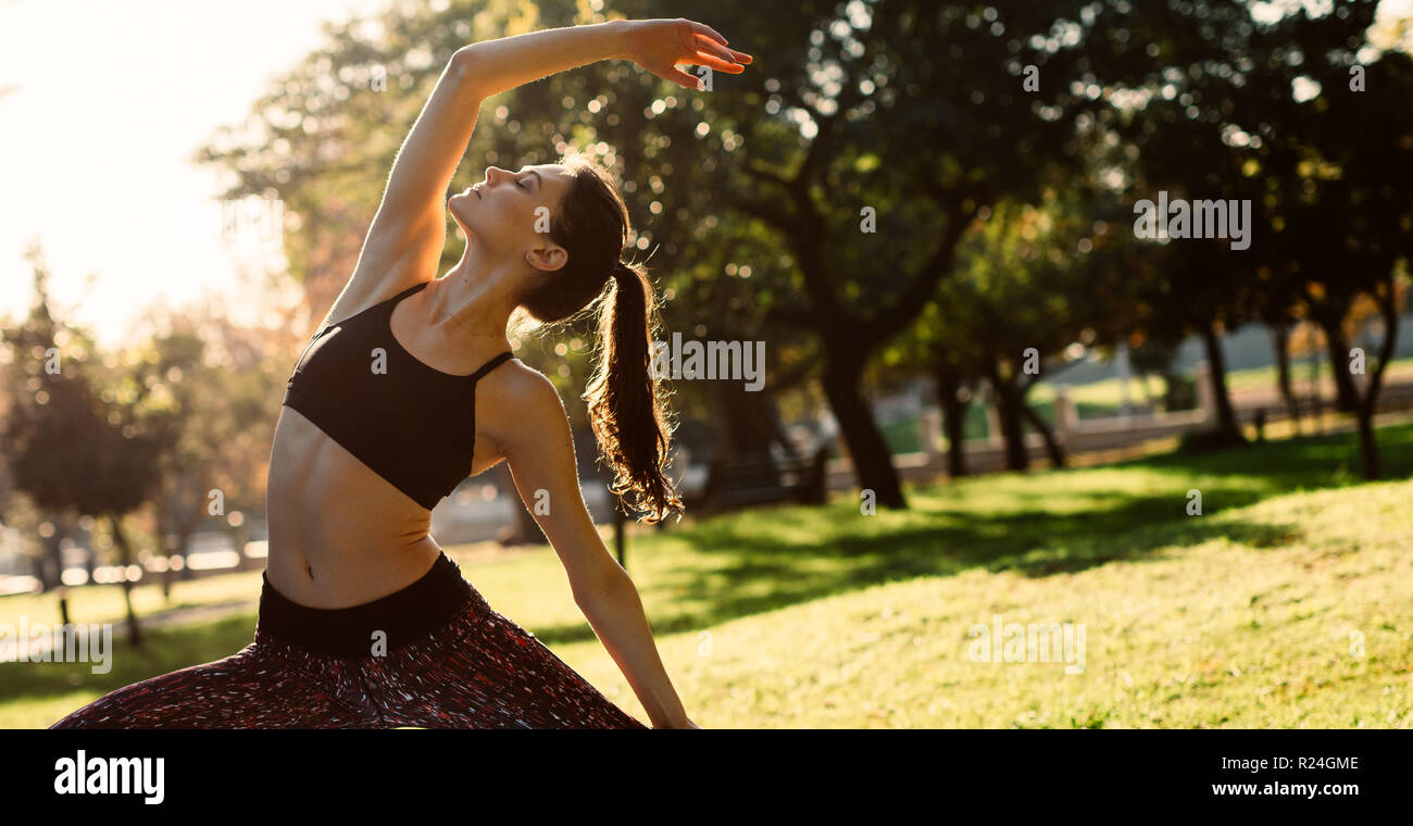 Healthy young woman bending backwards and stretching at park. Female ...