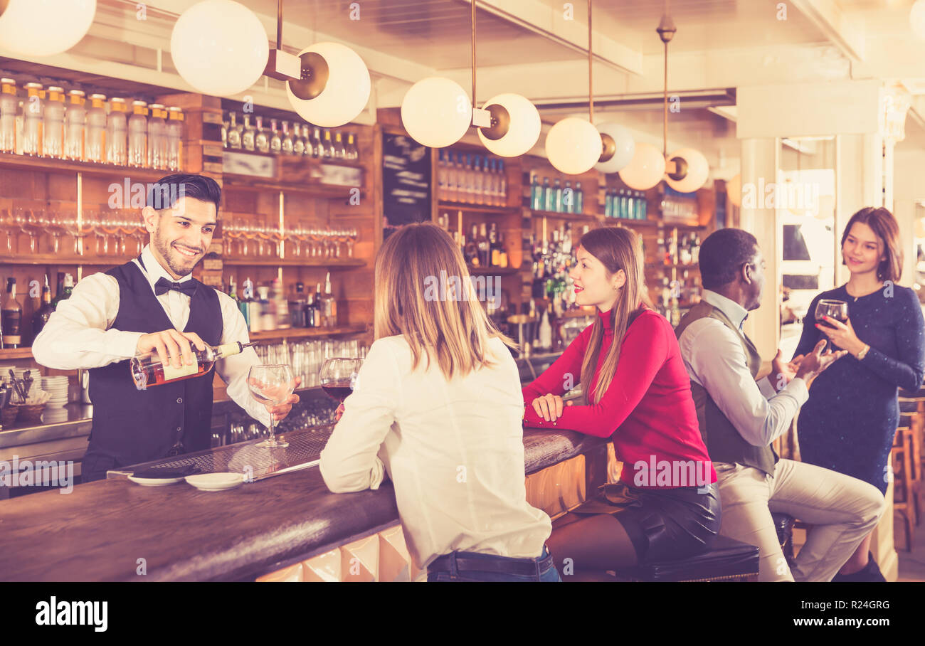 Joyful people are relaxing near bar counter and drinking alcohol in ...