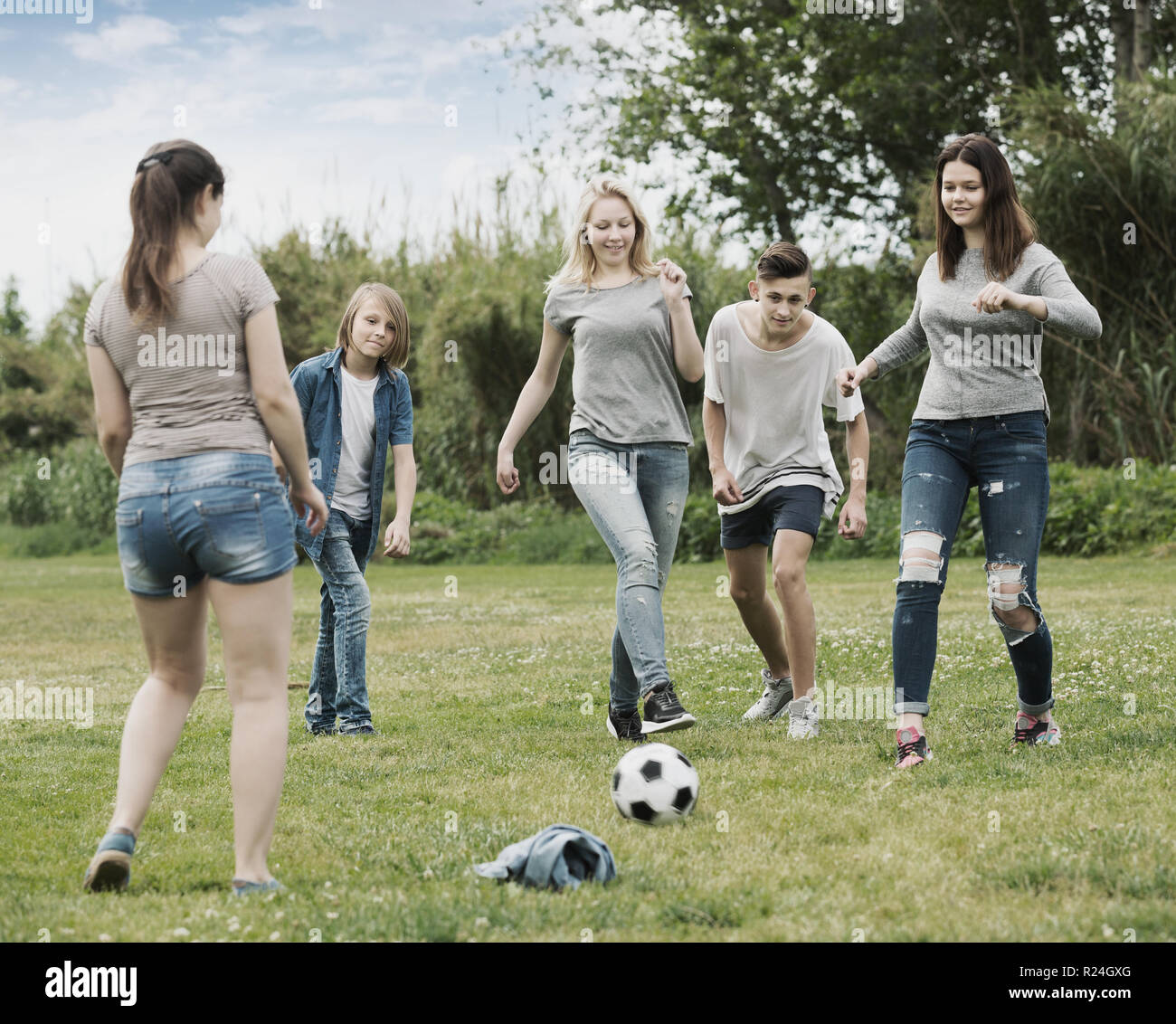 Three positive girls and two boys teenagers friends running with ball ...