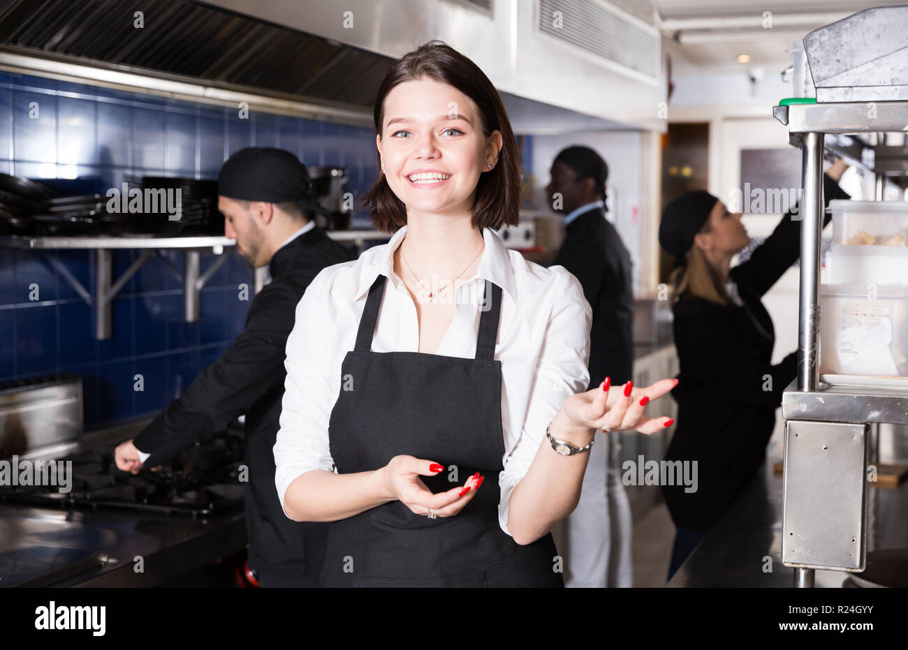 Portrait of female waiter who is standing with order on kitchen in ...