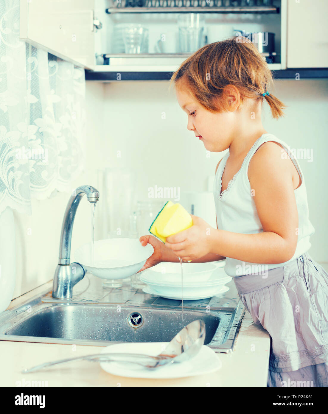 Serious little child washing dishes at domestic kitchen Stock Photo - Alamy