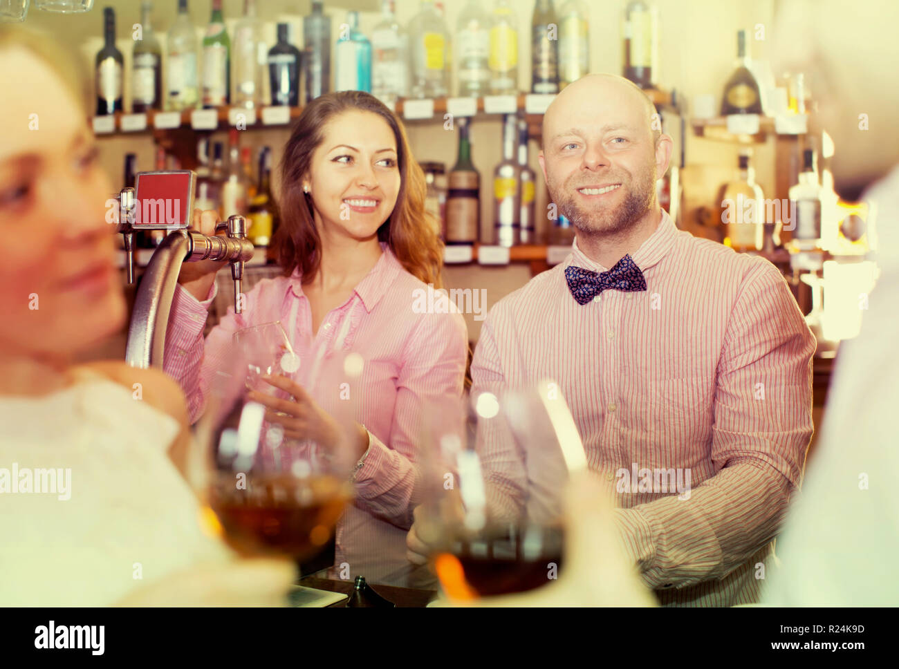 Positive happy bartender entertaining guests at a bar counter Stock ...