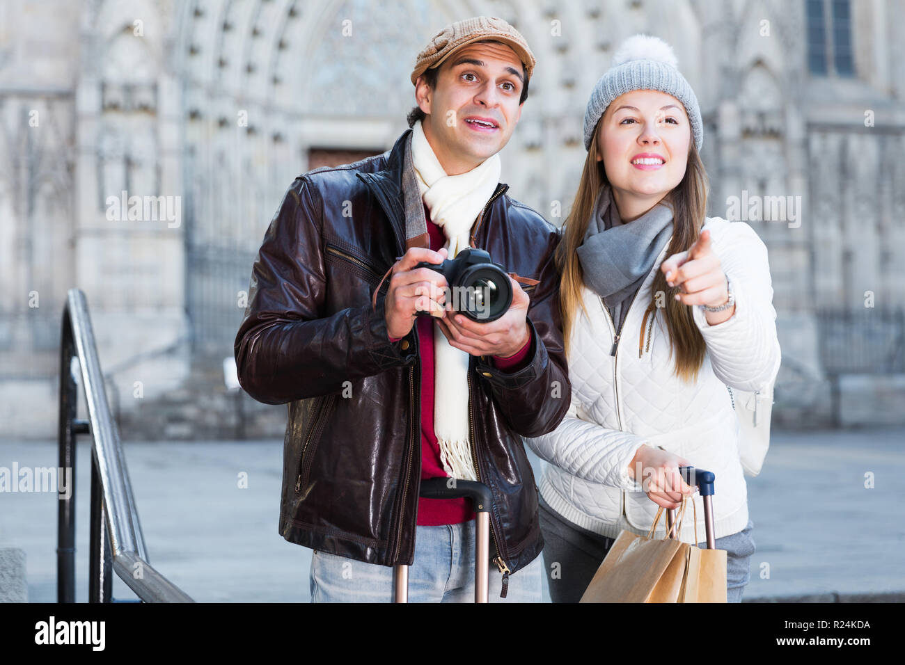 happy atractive adult male and female in the historic center pointing ...