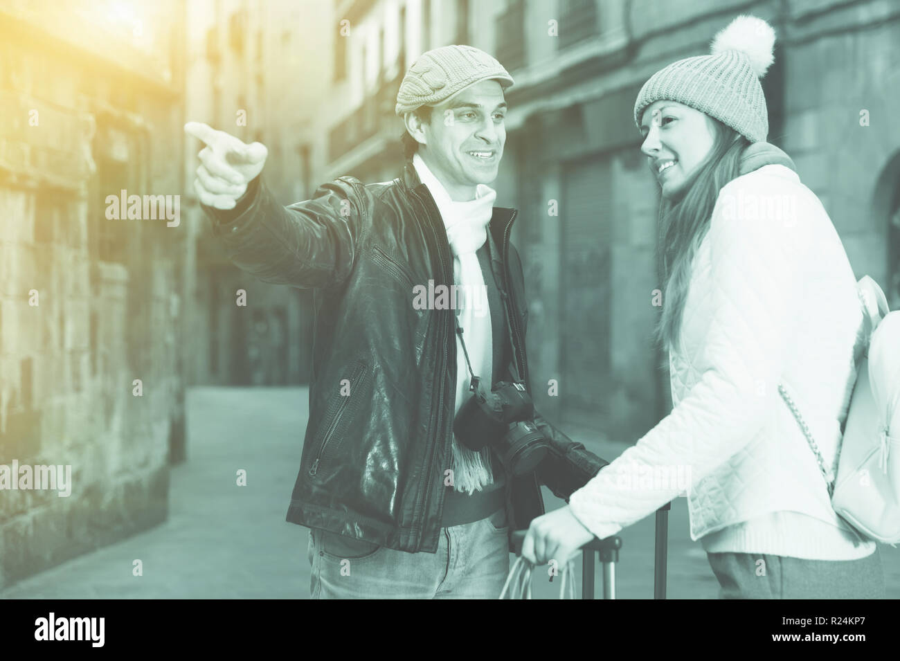 Adult travelers in hats and scarfs pointing finger on historical object ...