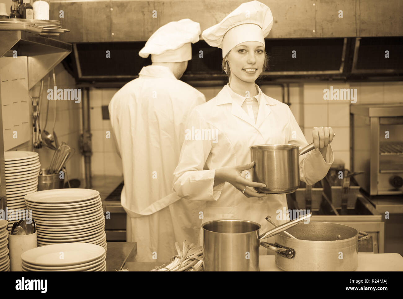 Positive head-cooks cooking at professional kitchen in the restaurant ...