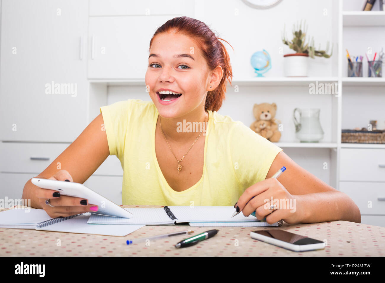 positive teenager girl taking notes while studying at home Stock Photo ...