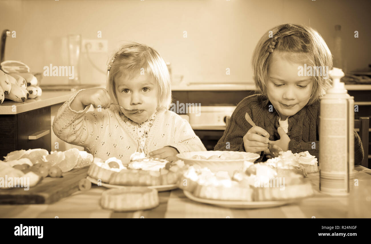 Kids eating delicious pastry with cream in the kitchen Stock Photo - Alamy
