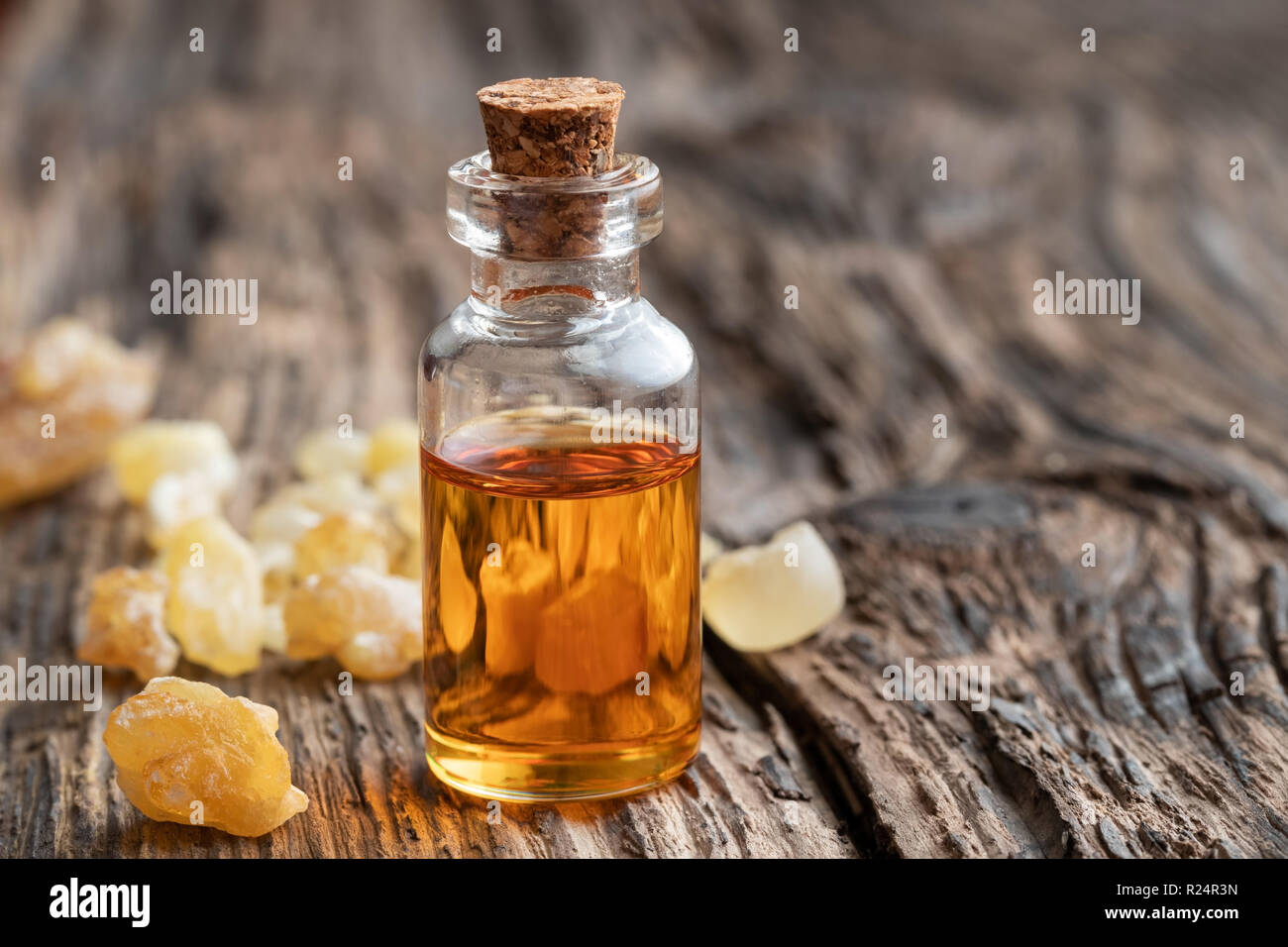 A bottle of essential oil with frankincense resin crystals on a rustic ...
