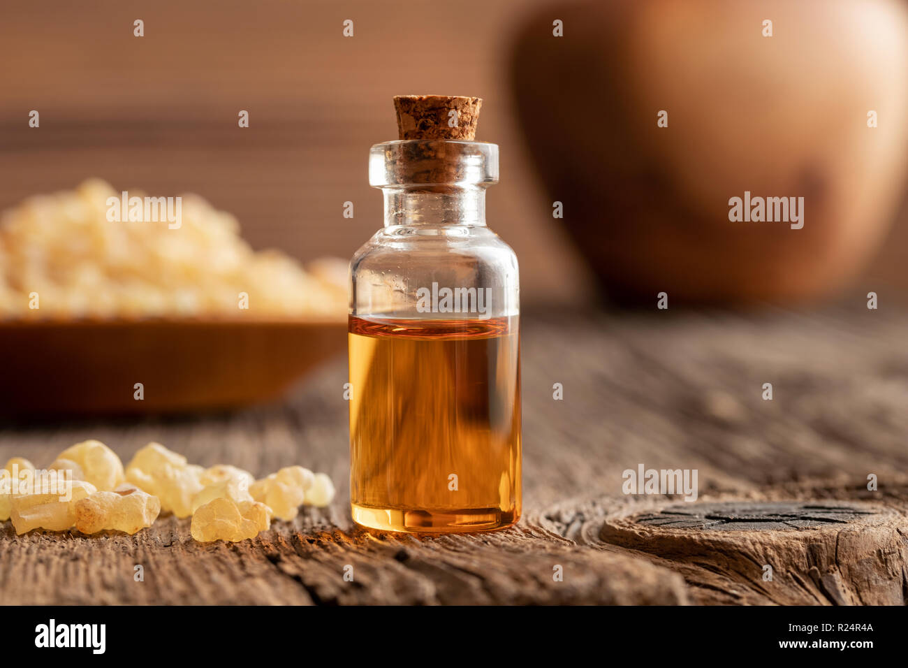 A bottle of essential oil with frankincense resin crystals on a table ...