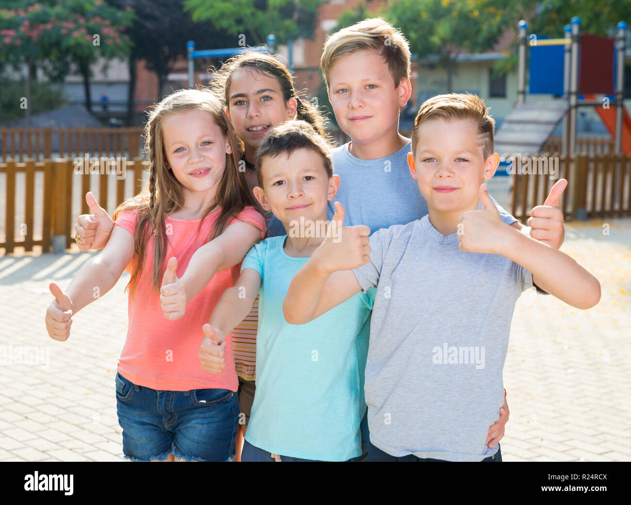 Glad kids posing at the playground together and thumbs up Stock Photo ...