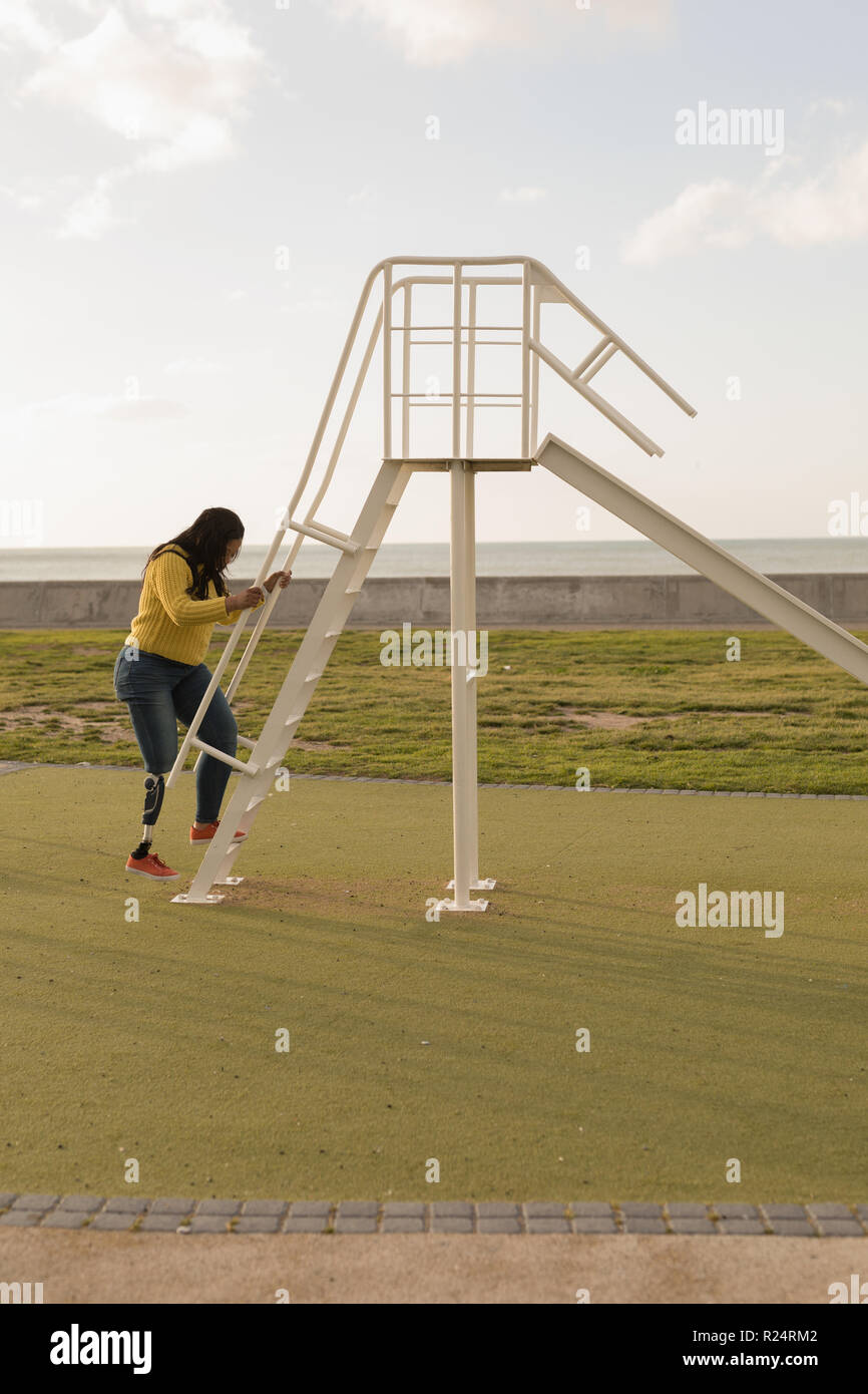 Disable woman ascending on ladder slide Stock Photo - Alamy