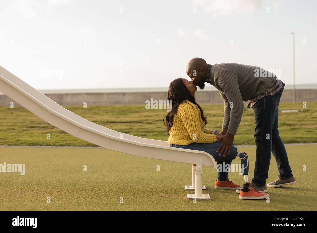 Couple kissing on ladder slide Stock Photo - Alamy