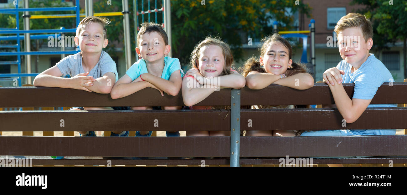Five glad children sitting on a bench at the playground Stock Photo - Alamy