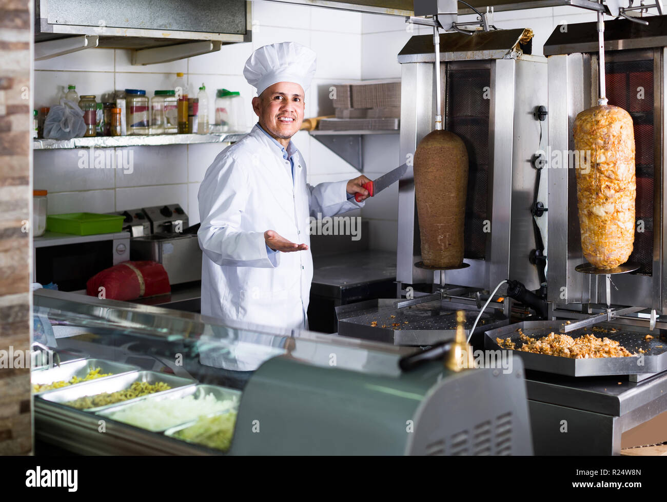 smiling russian mature man chef wearing uniform cutting meat for kebab ...