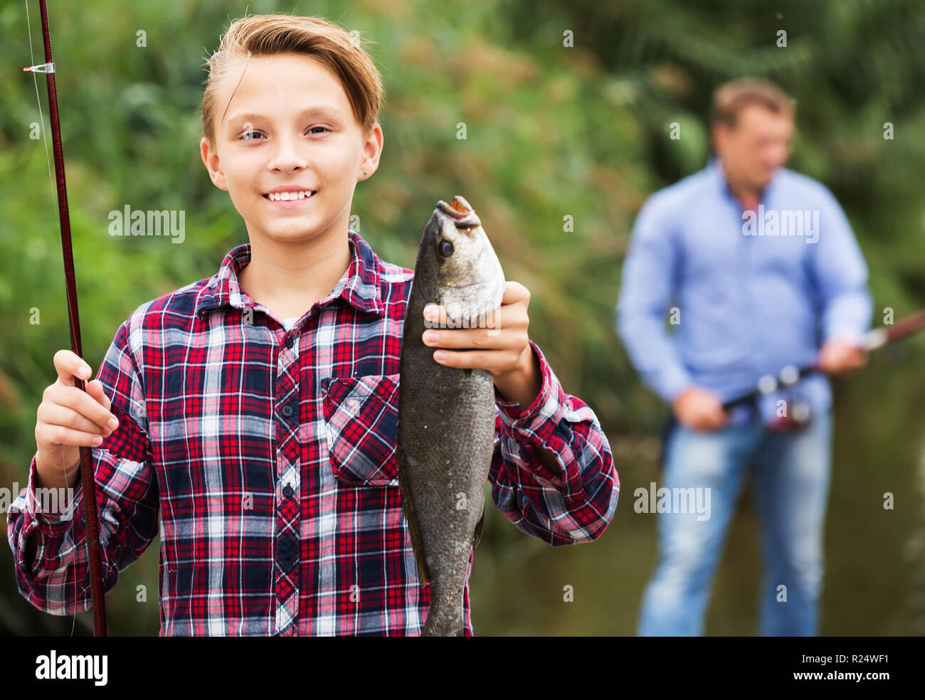 Glad teenager boy showing catch fish he holding in hands Stock Photo ...