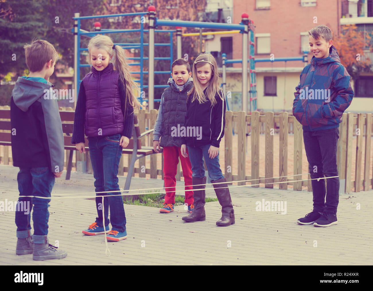 Happy positive children playing rubber band jumping game and laughing ...