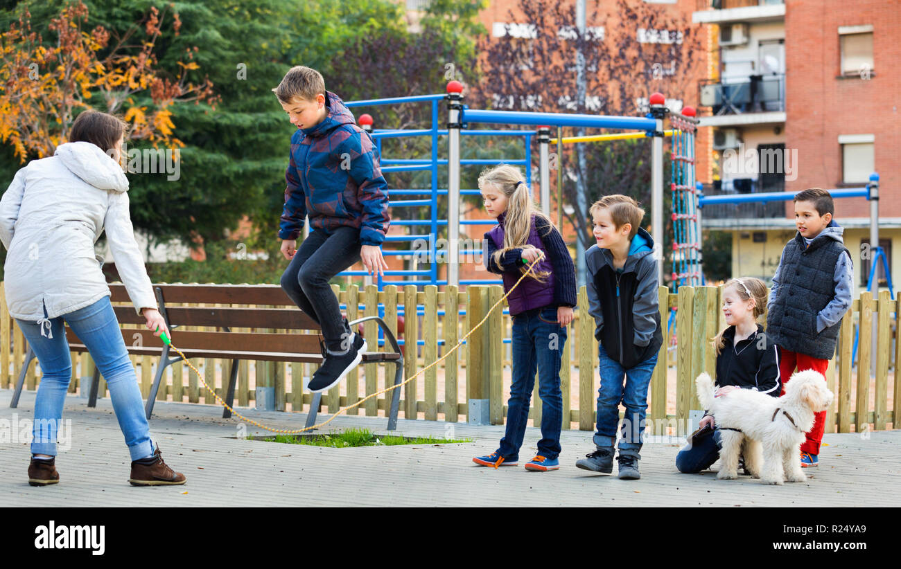 Glad cheerful kids playing in jump rope game at city street Stock Photo ...