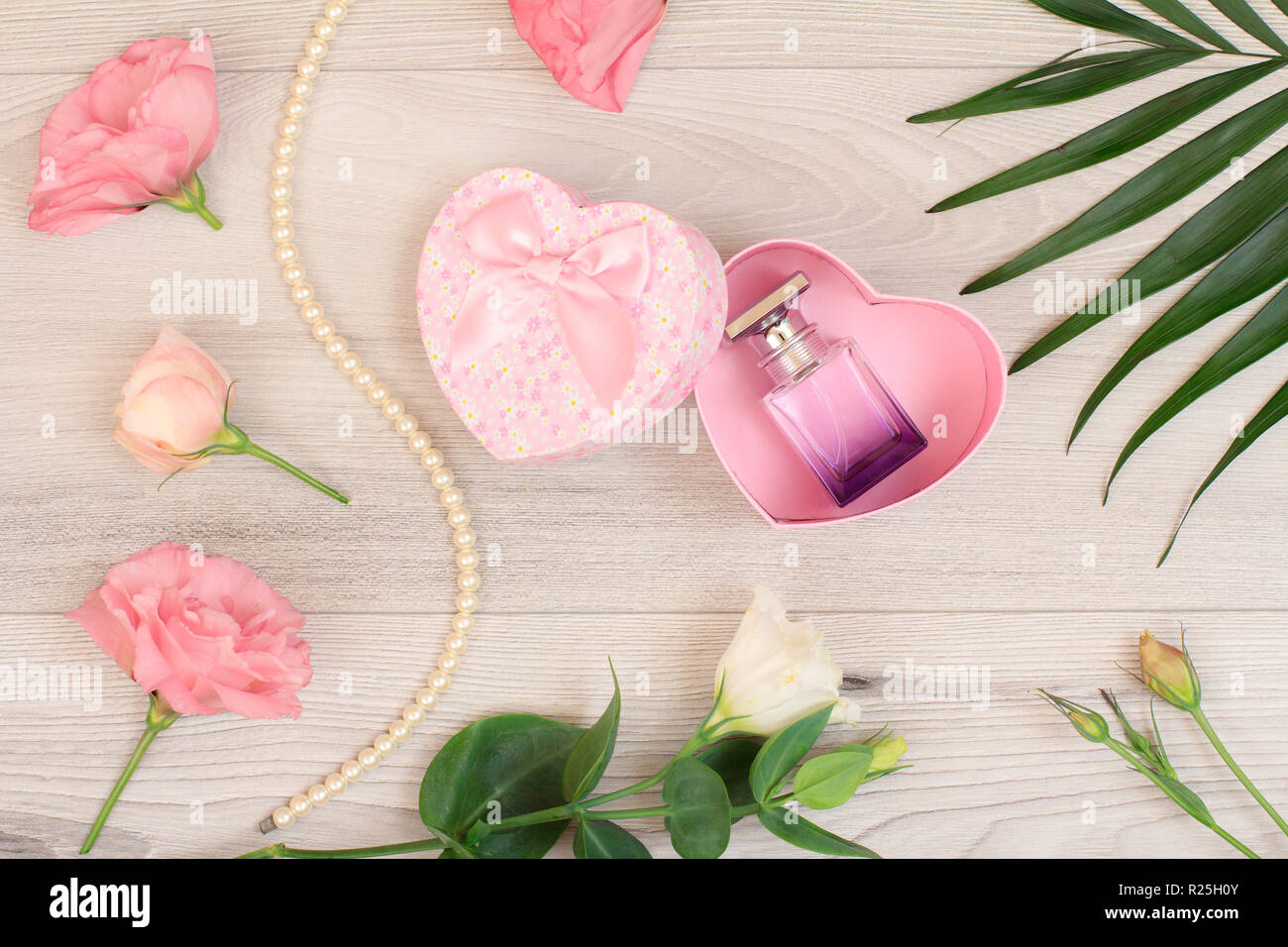 Gift box in heart shape with bottle of perfume and pink flowers and ...